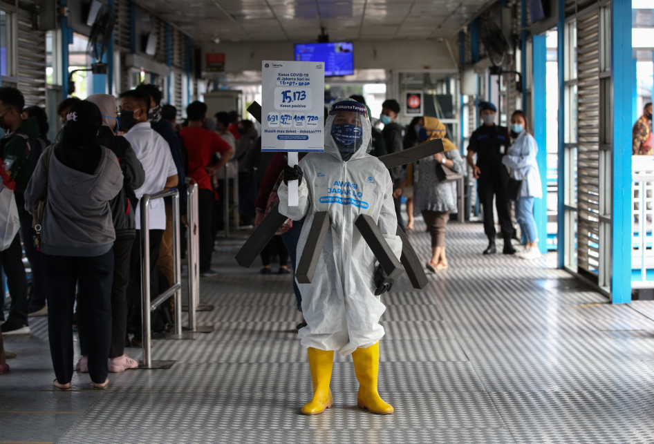 Aksi Maskot Manusia Covid di Koridor Halte Transjakarta